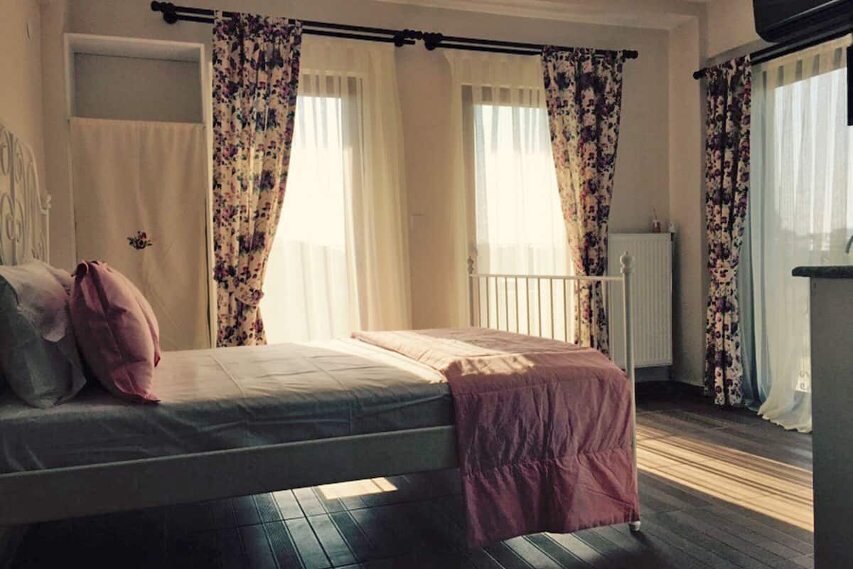 Quarto com cama, cortinas, radiador e janela.