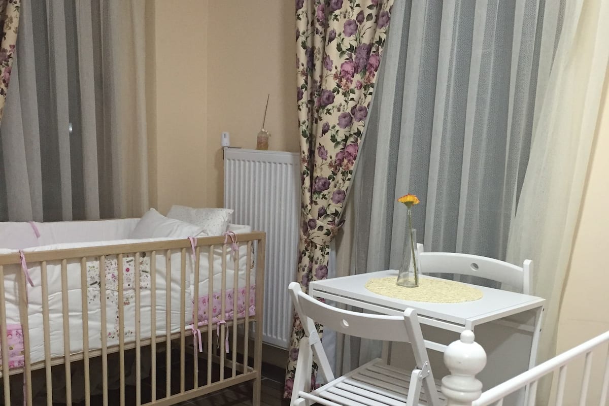 Quarto de bebê com berço, cadeirinha e radiador.