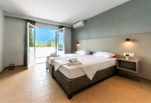 Quarto de hotel moderno com uma cama grande, uma mesa de cabeceira e um ar condicionado.