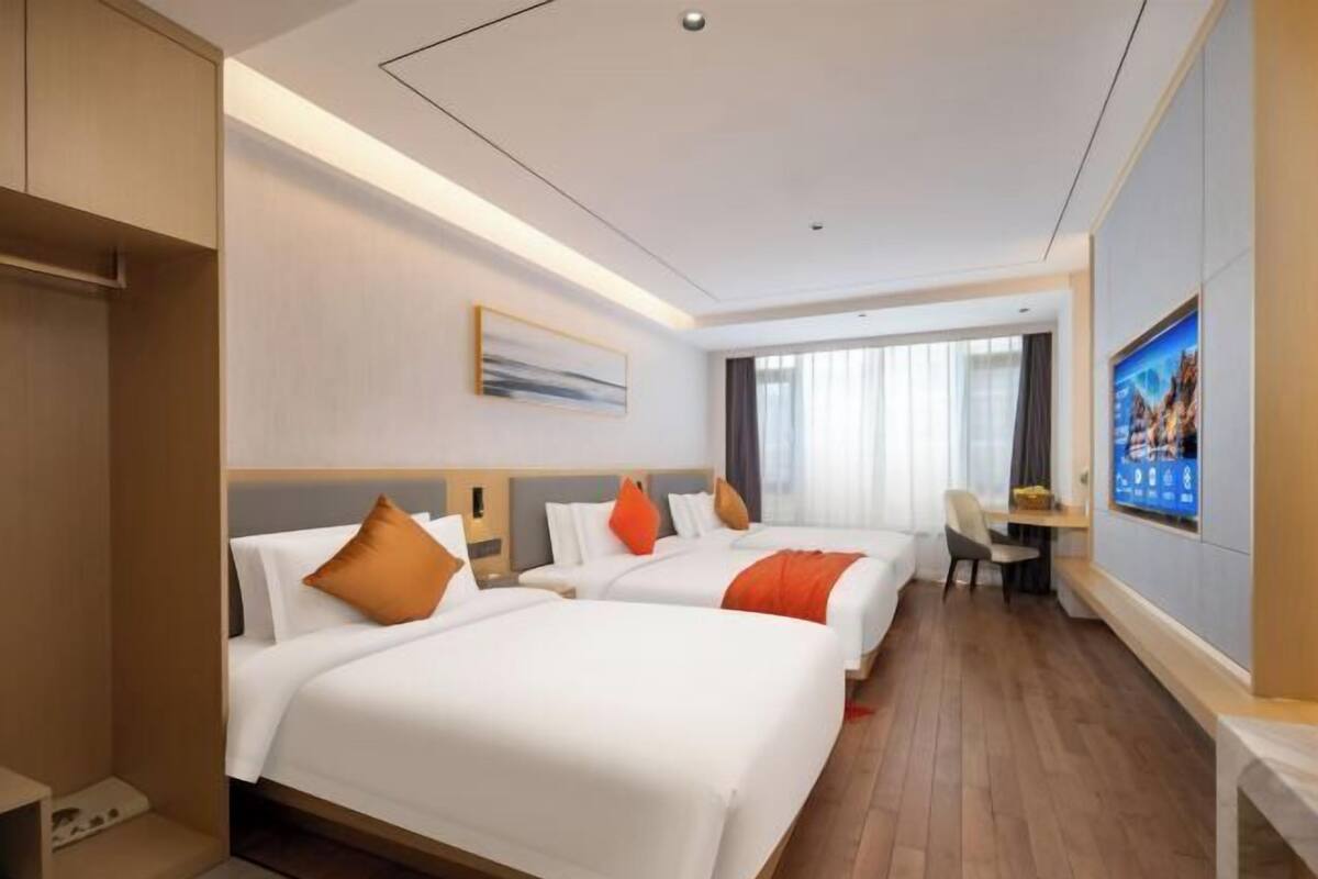 Quarto de hotel com duas camas, uma escrivaninha e uma televisão.