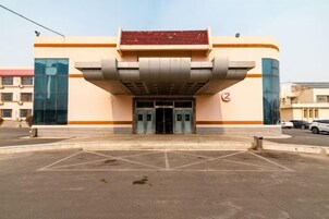 Um edifício com fachada curva, grandes janelas de vidro e entrada destacada com a placa de número '2'.