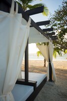 Na praia, areia branca, espreguiçadeiras, guarda-sóis 