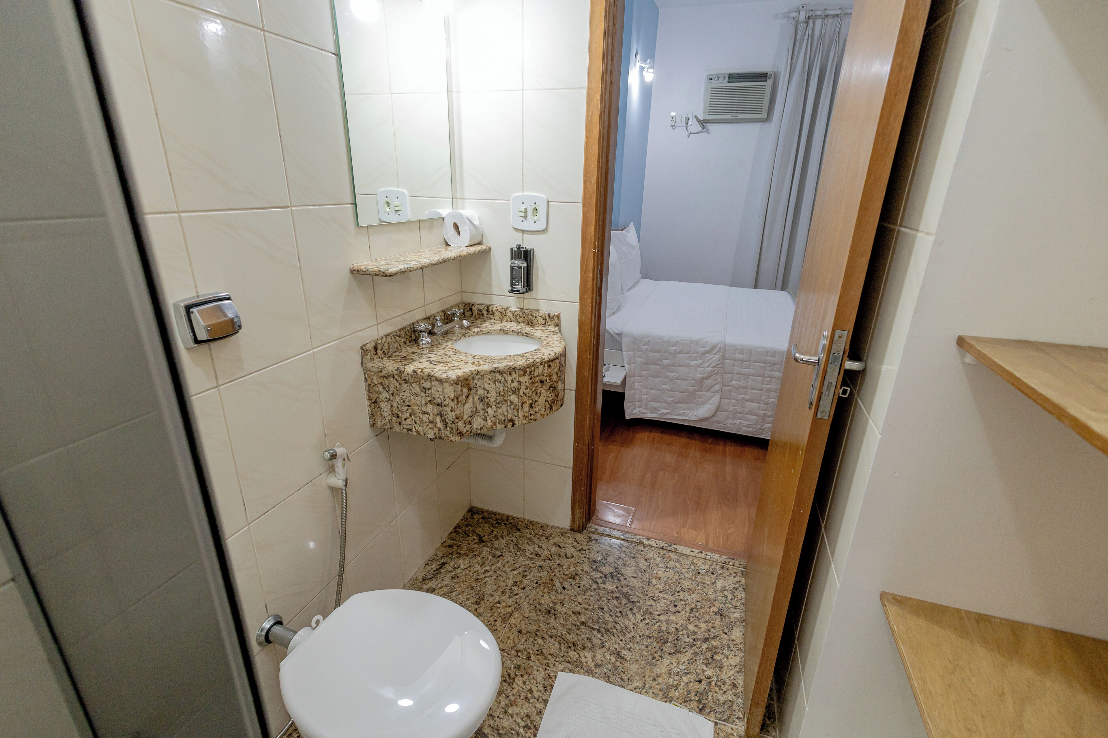 Casa de banho compacta com sanita, lavatório e chuveiro.