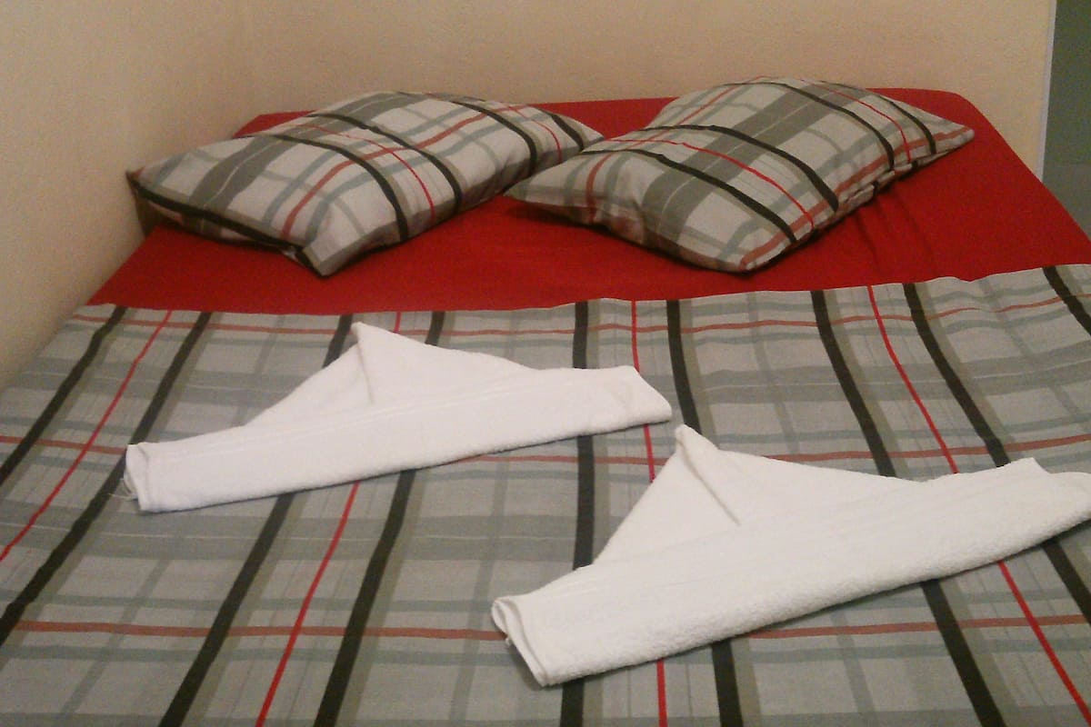 Uma cama com roupa de cama xadrez e duas toalhas brancas dobradas.