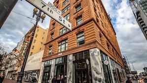 Edifício em esquina com grande placa indicando 7th Street e entrada visível para um prédio com fachada de vidro.