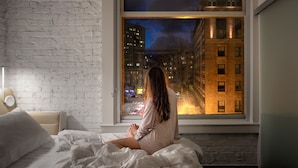Quarto com uma grande janela com vista para a paisagem urbana à noite.