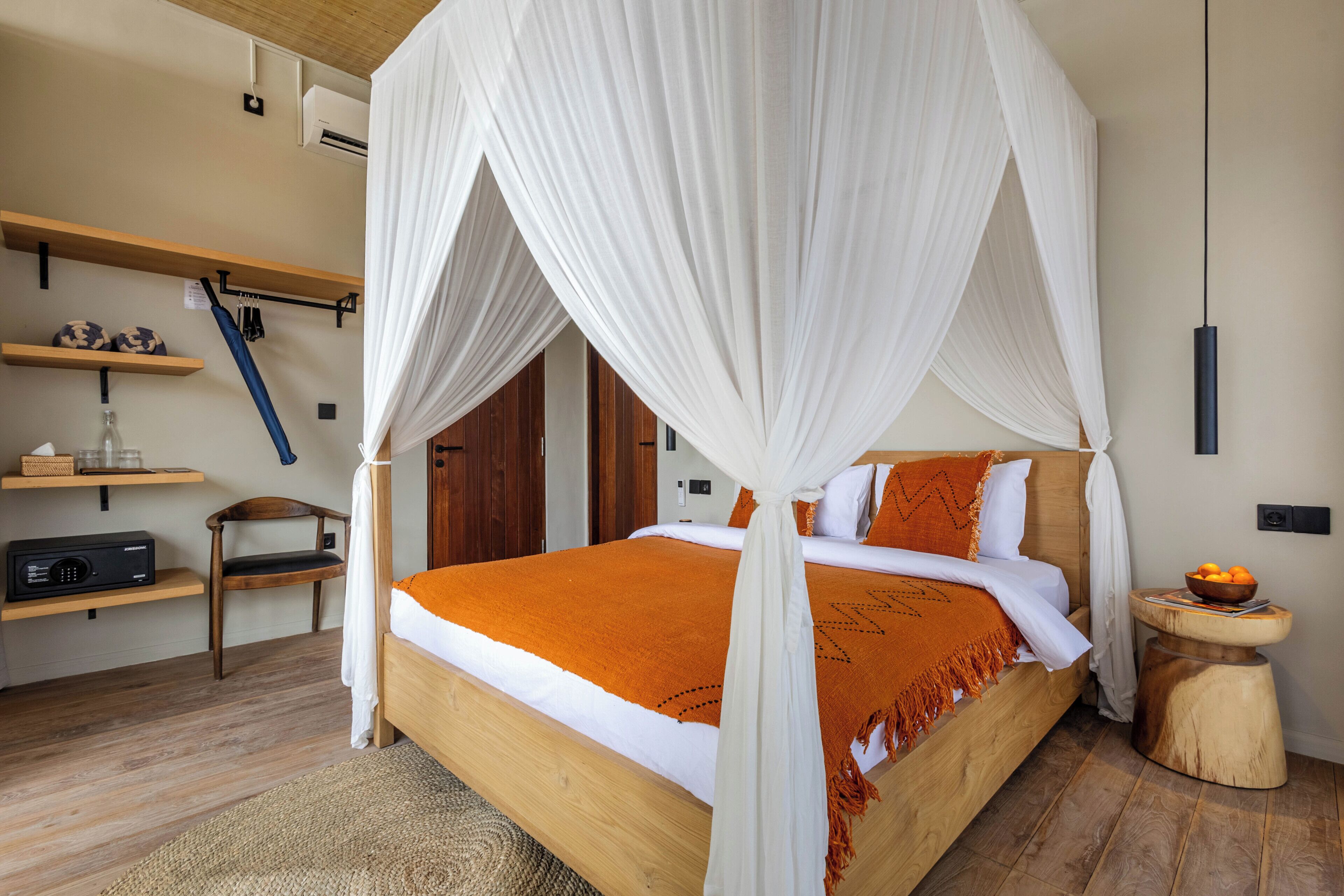 Quarto com cama de dossel, cabeceira de madeira e mesa de cabeceira com uma cesta de frutas.