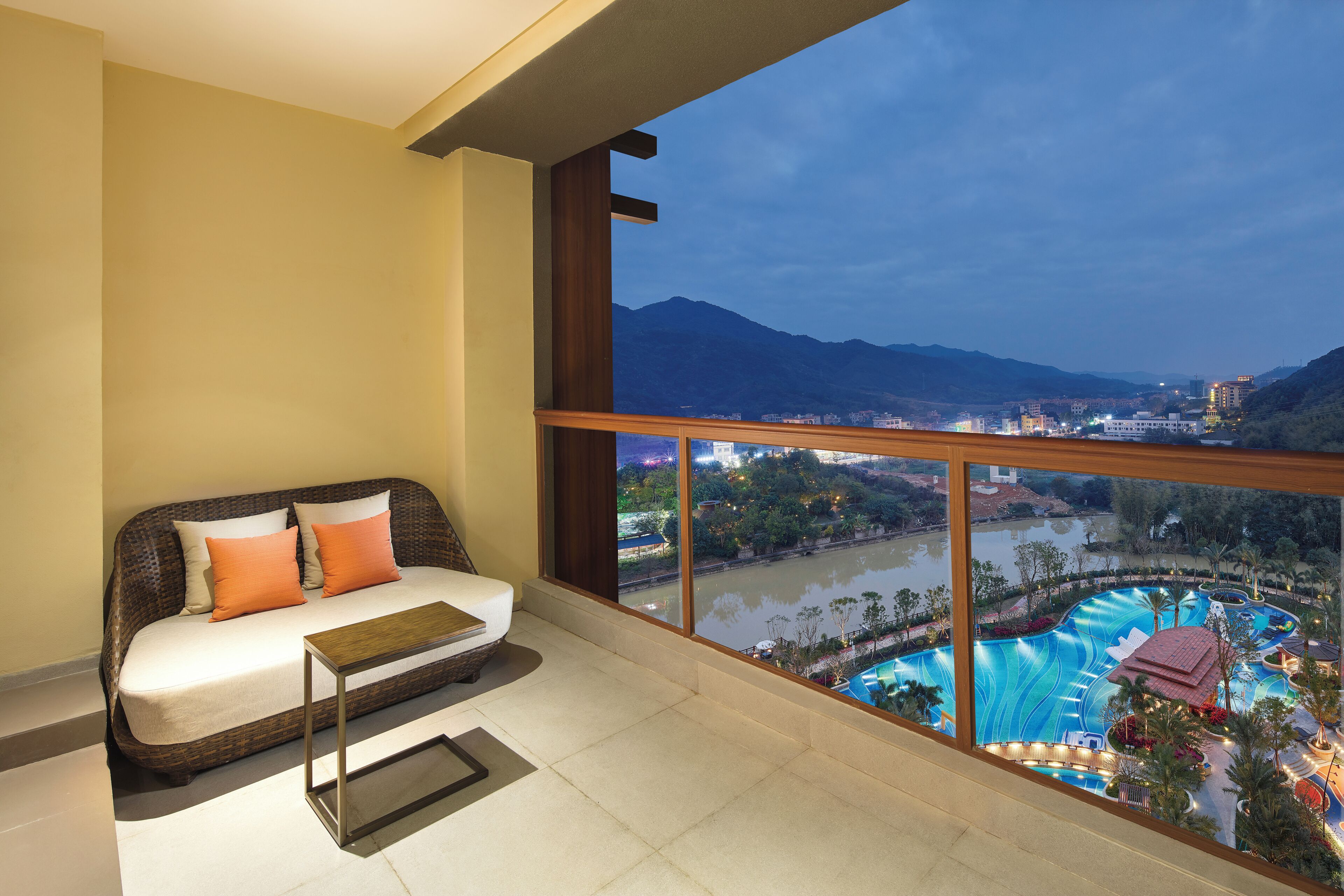 Varanda com sofá e vista para uma piscina e montanhas.