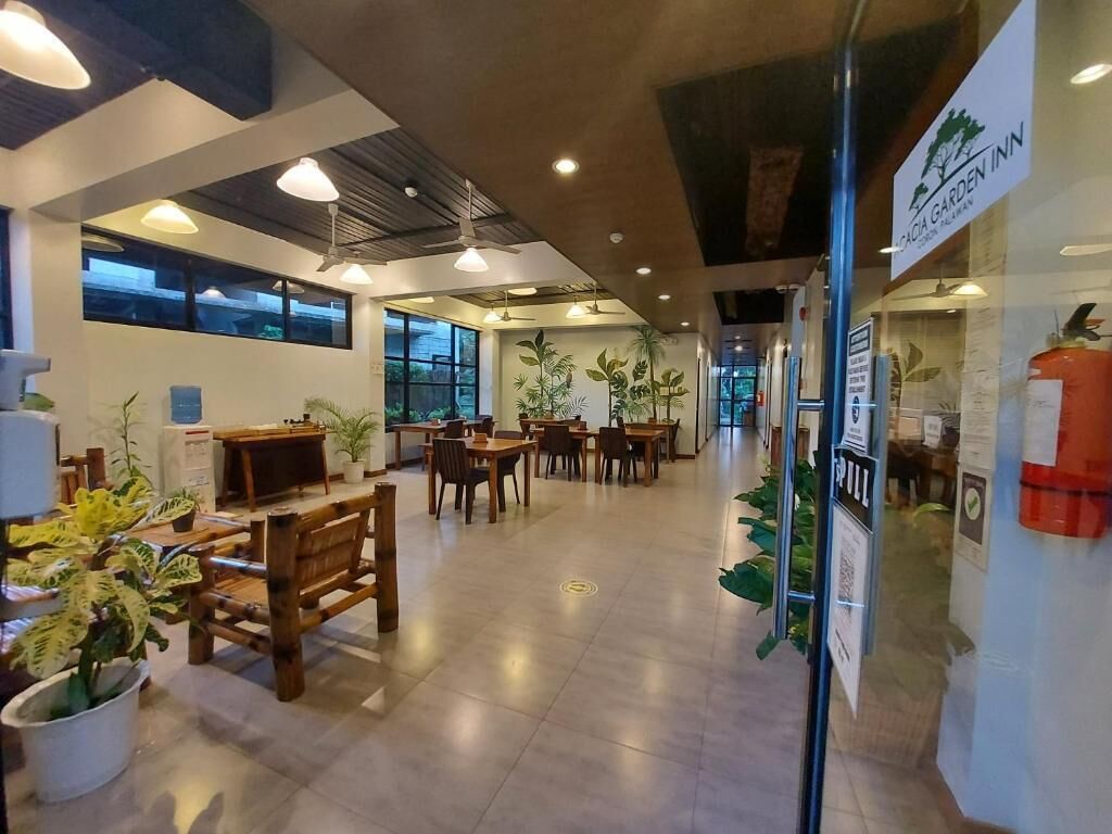 Amplo espaço interno com várias mesas e cadeiras, teto com iluminação embutida e uma placa com o nome do estabelecimento.