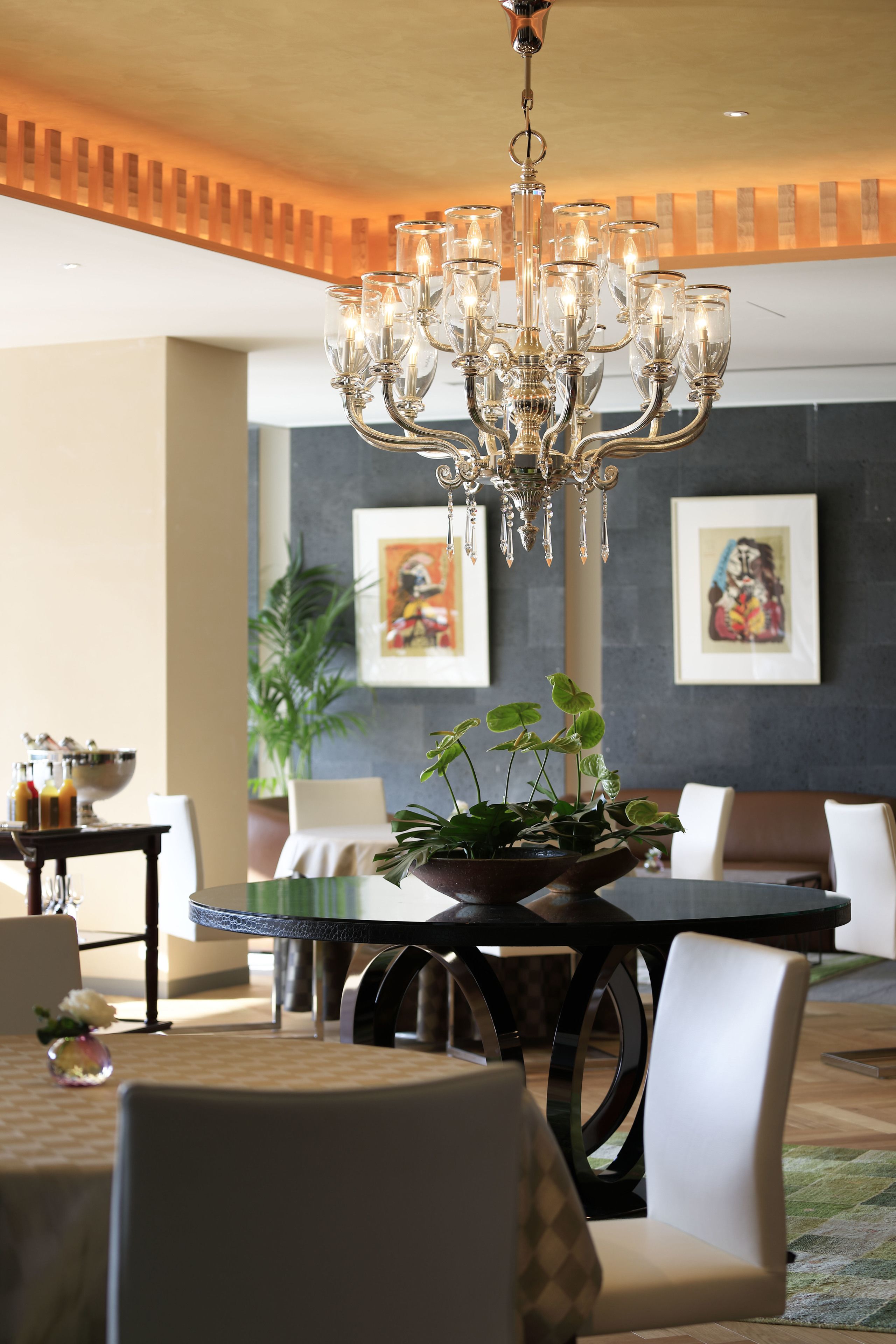 Uma sala de jantar com um candelabro, uma mesa com cadeiras e obras de arte nas paredes.