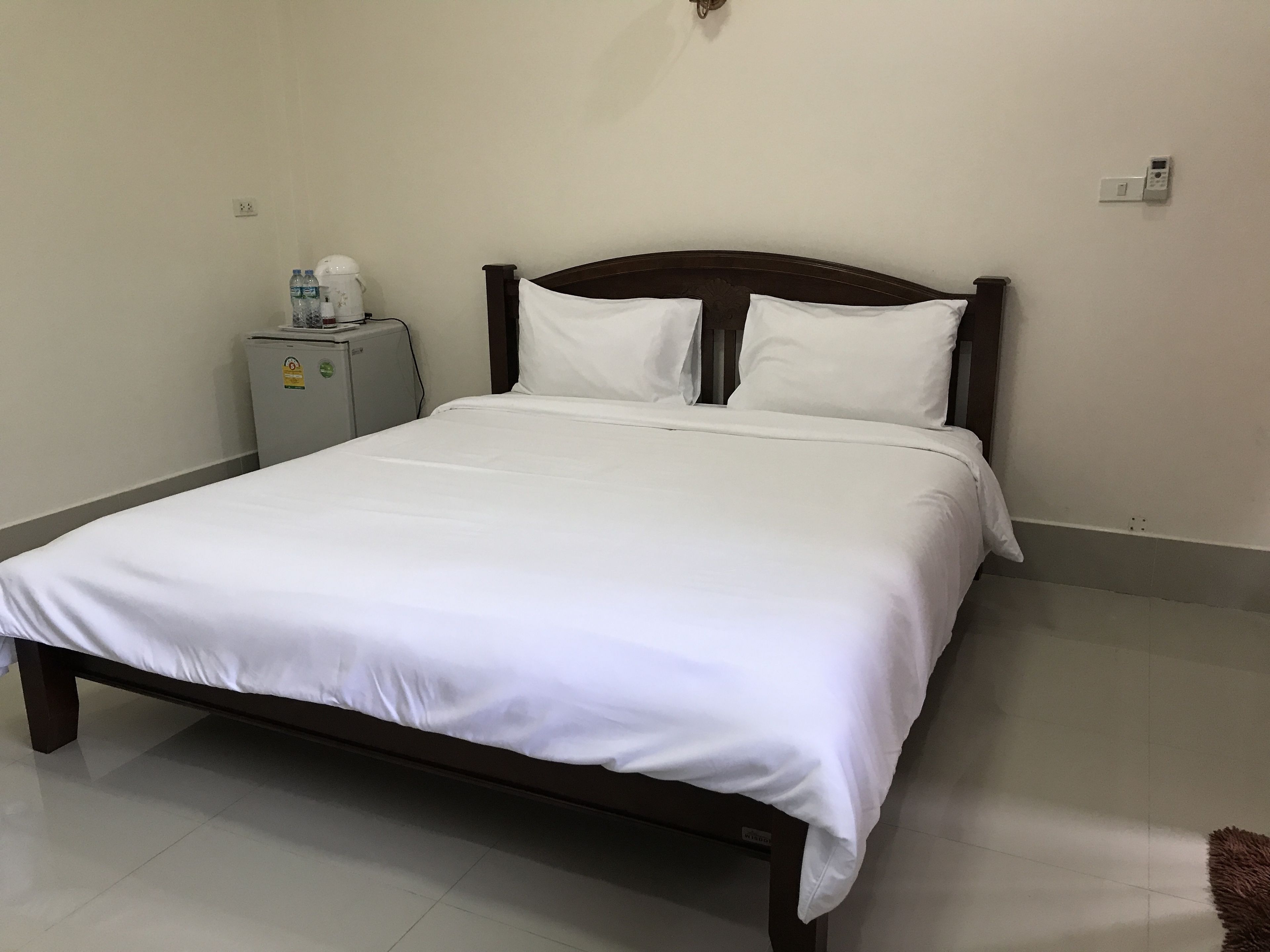 Cama arrumada com roupa de cama branca em quarto de hotel.