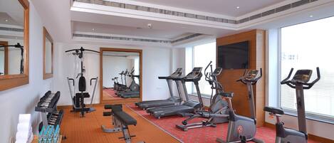Academia de hotel com esteiras, elípticos e equipamentos de musculação.