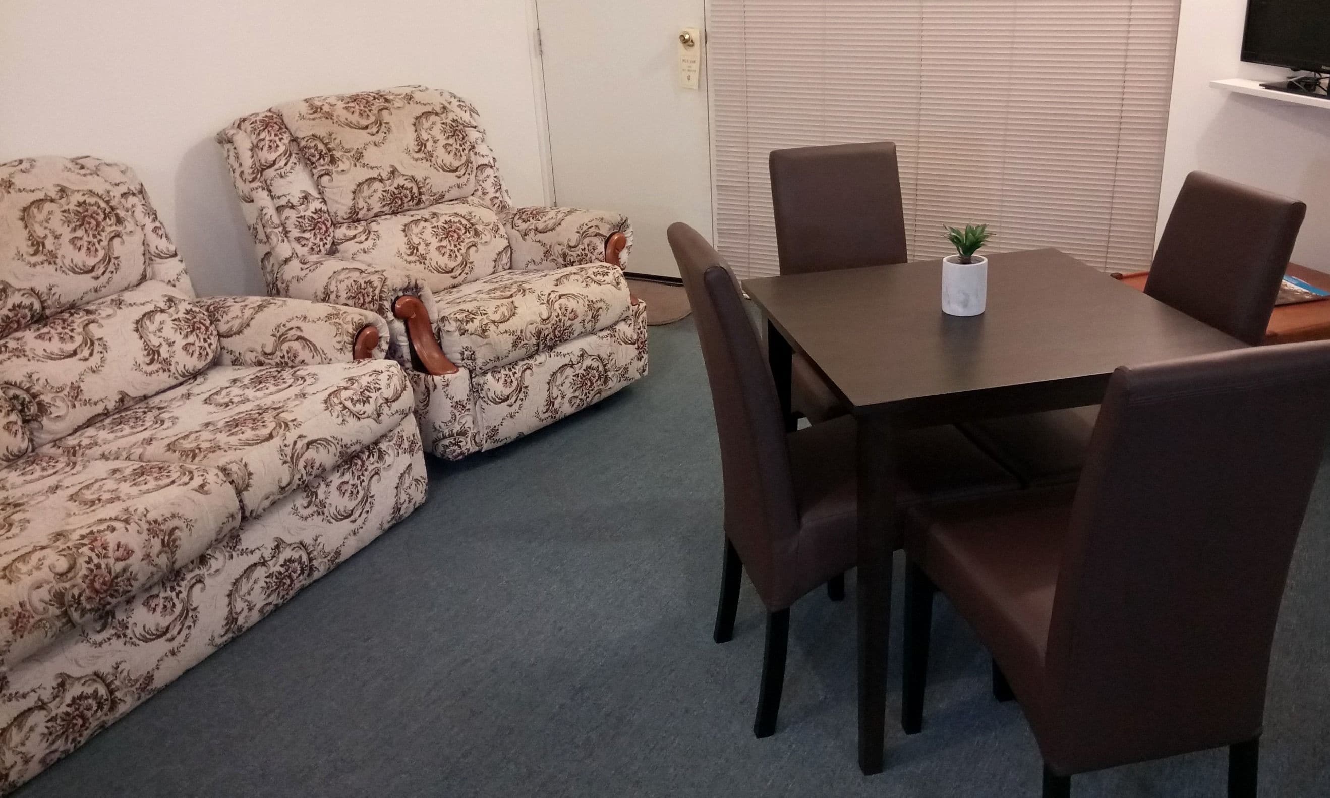 Uma sala de estar com sofá e uma mesa de jantar com cadeiras.