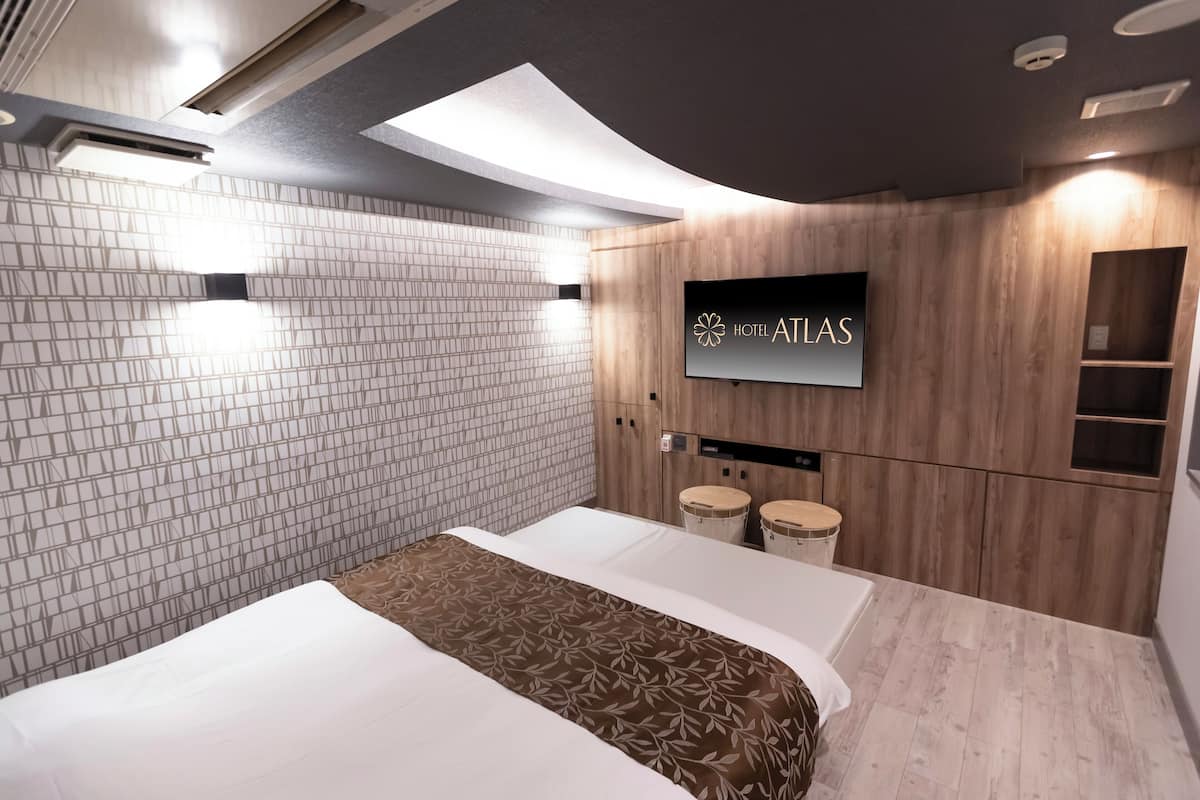 Quarto de hotel moderno com uma cama grande, uma televisão de tela plana na parede e uma parede de destaque em madeira.