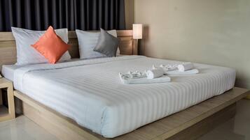 Uma cama bem arrumada com roupa de cama branca, uma cabeceira de madeira e uma mesa de cabeceira com abajur.