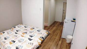 Quarto pequeno e limpo com uma cama, frigorífico e sanita.