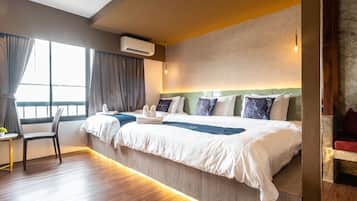 Quarto de hotel com duas camas, uma cadeira, ar condicionado e uma janela com cortinas.
