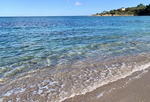 Perto da praia, areia branca, guarda-sóis, toalhas de praia 