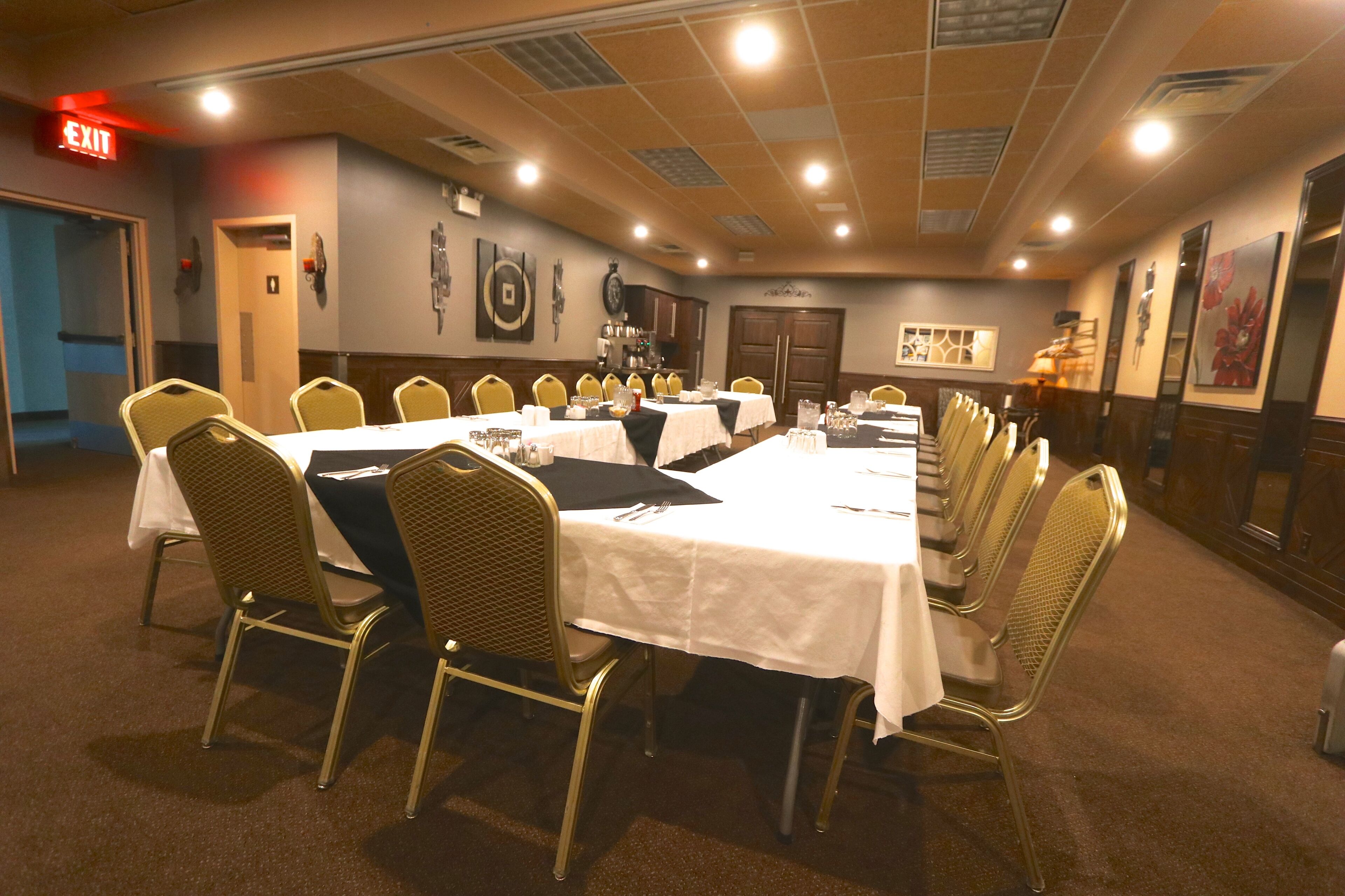 Uma sala de conferências com várias mesas e cadeiras, equipada com placas de identificação e louça posta.