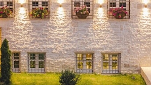 Um edifício de v ários andares com fachada de pedra e várias janelas, algumas com floreiras.
