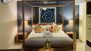 Uma cama com dossel e cabeceira floral, um candelabro, uma mesa de cabeceira com uma garrafa e copos, e um design de quarto moderno.