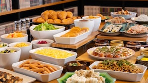 Buffet com diversos pratos e uma estante de livros ao fundo.