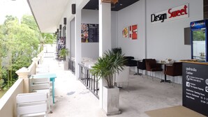 Um restaurante com mesas ao ar livre, um quadro de menu e uma placa com 'Design Sweet'.