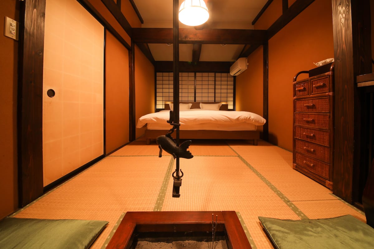 Um quarto japonês tradicional com tatame, futon, cómoda de madeira e divisória shoji.