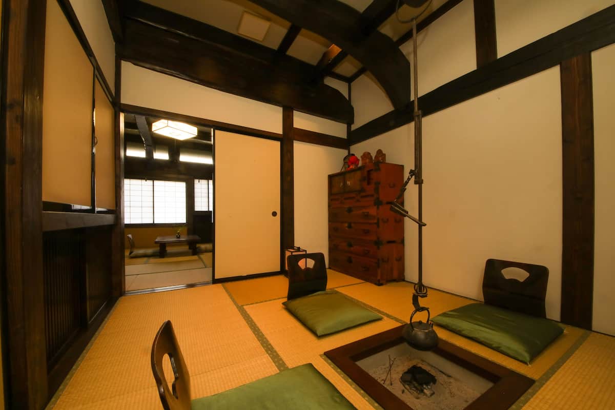 Um quarto japonês tradicional com tatames, um futon, um armário de madeira e um lampião pendurado.