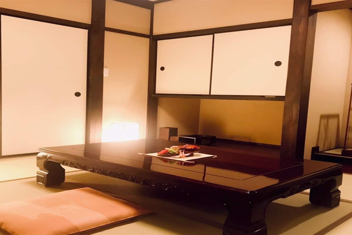 Um quarto japonês tradicional com tatames, uma mesa baixa com um assento acolchoado e portas deslizantes.