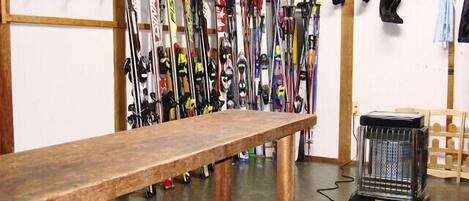 Quarto com uma mesa de madeira e pranchas de esqui e snowboard penduradas na parede.