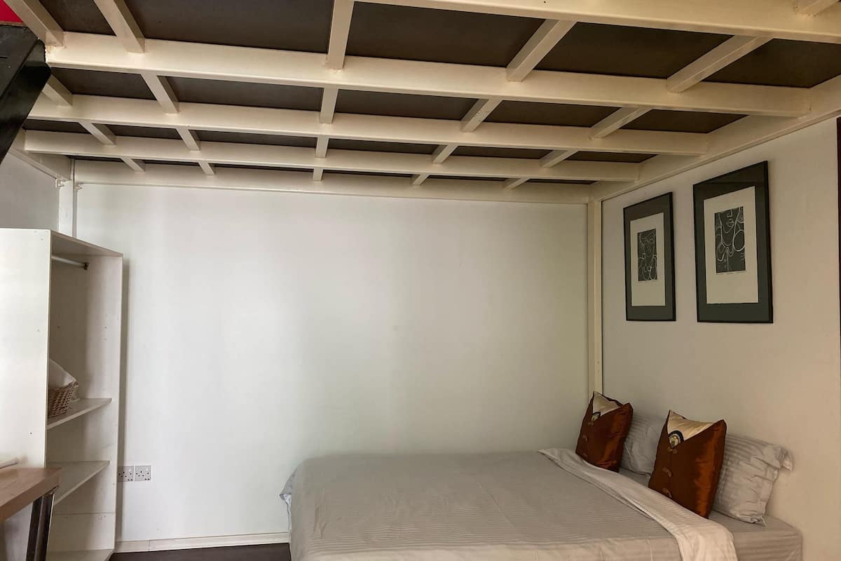 Quarto com cama, guarda-roupa e duas molduras na parede.