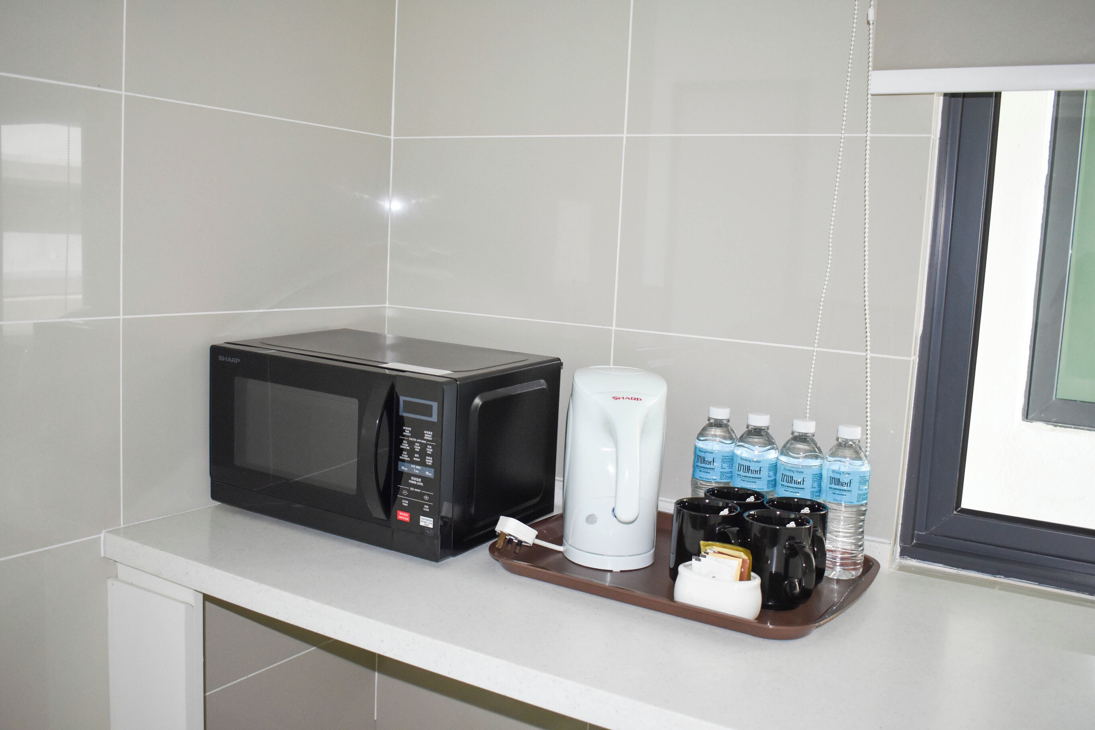 Uma cozinha com micro-ondas, cafeteira e garrafas de água em um suporte.