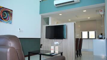 Uma sala de estar moderna com televisão de tela plana na parede, um sofá de couro marrom, uma mesa de centro de vidro e um quadro abstrato colorido.