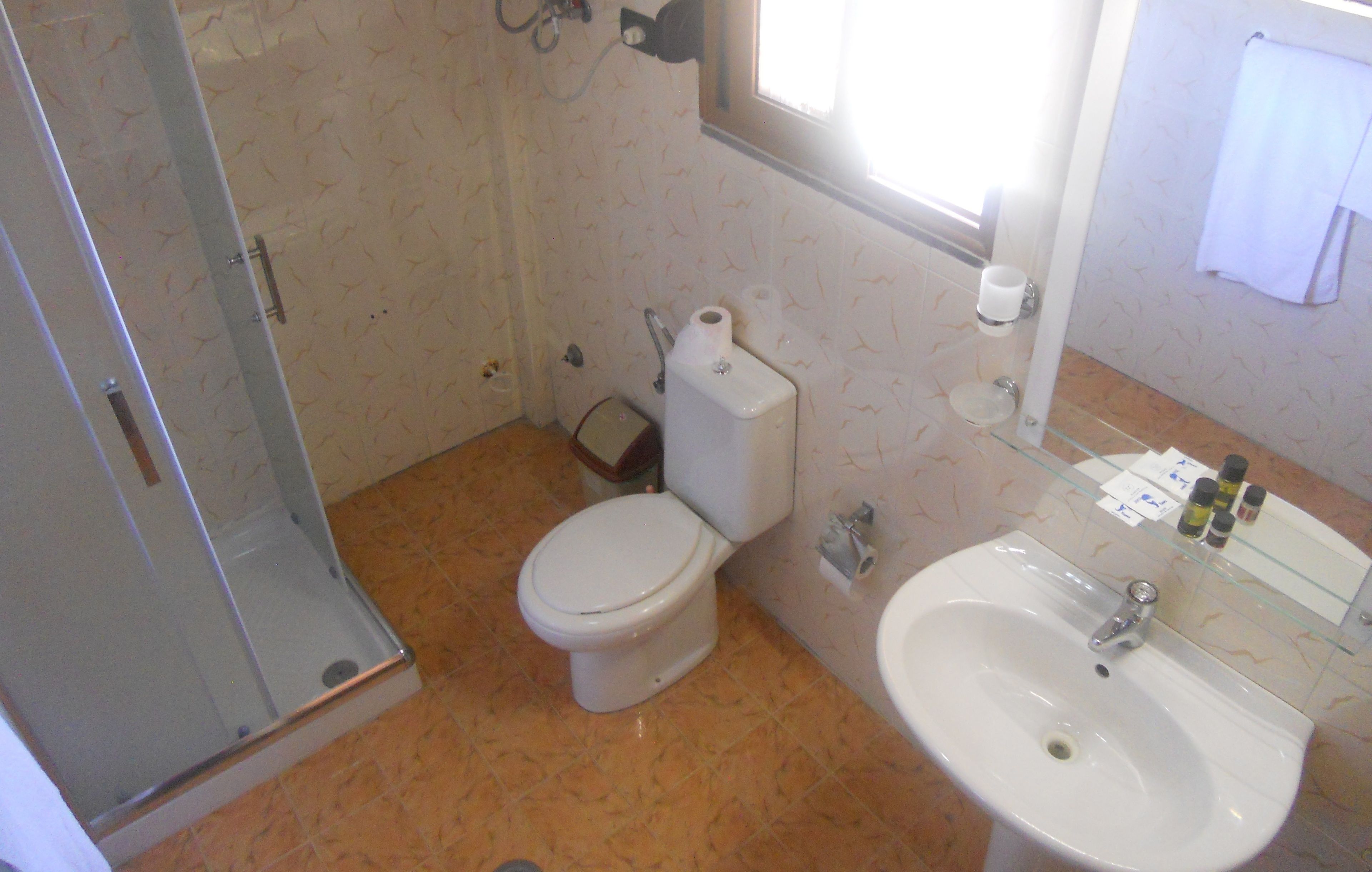 Uma casa de banho com sanita, lavatório e chuveiro.