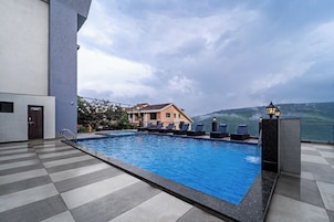 Piscina no terraço com espreguiçadeiras e vista para a paisagem ao redor.
