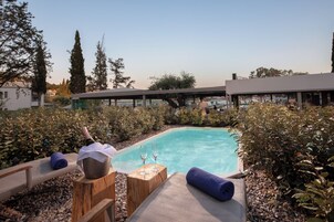 Uma área de piscina com deck de madeira, uma espreguiçadeira e uma garrafa de champanhe.