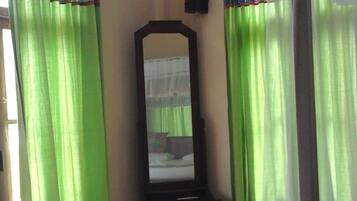 Quarto com um espelho grande, cómoda de madeira e cortinas coloridas.