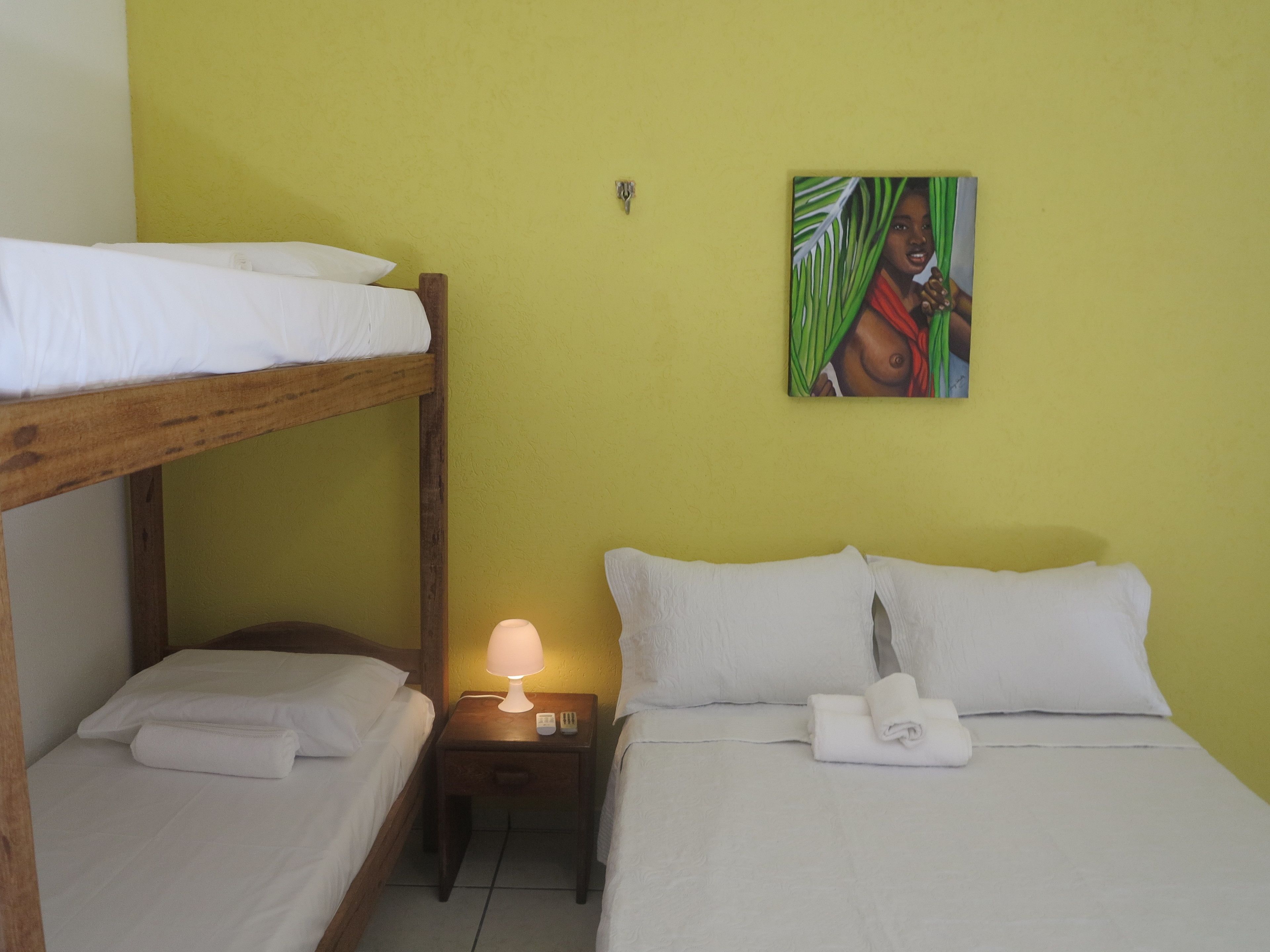 Um quarto com duas beliches, uma mesa de cabeceira com abajur e um quadro na parede.