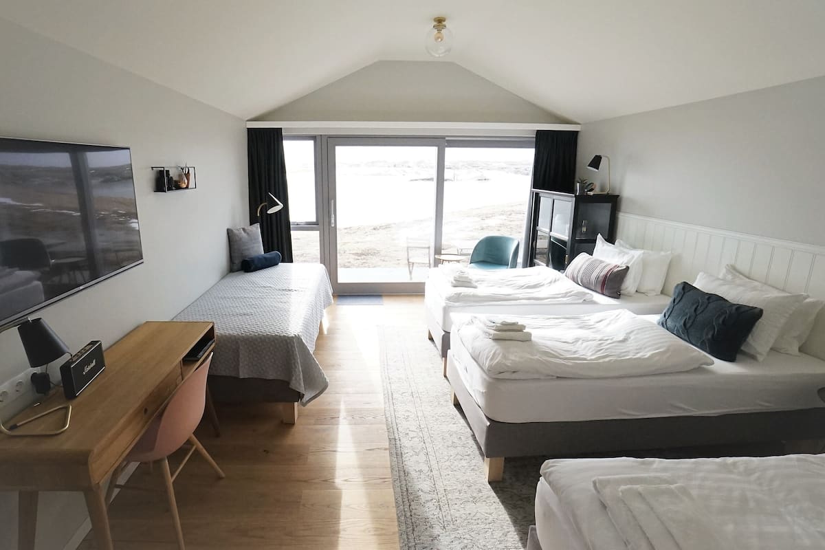 Quarto de hotel com duas camas, uma escrivaninha, uma cadeira e uma televisão.