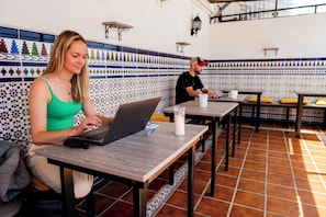 Uma pessoa usando um laptop em uma mesa em um quarto com paredes e chão de azulejos estampados.