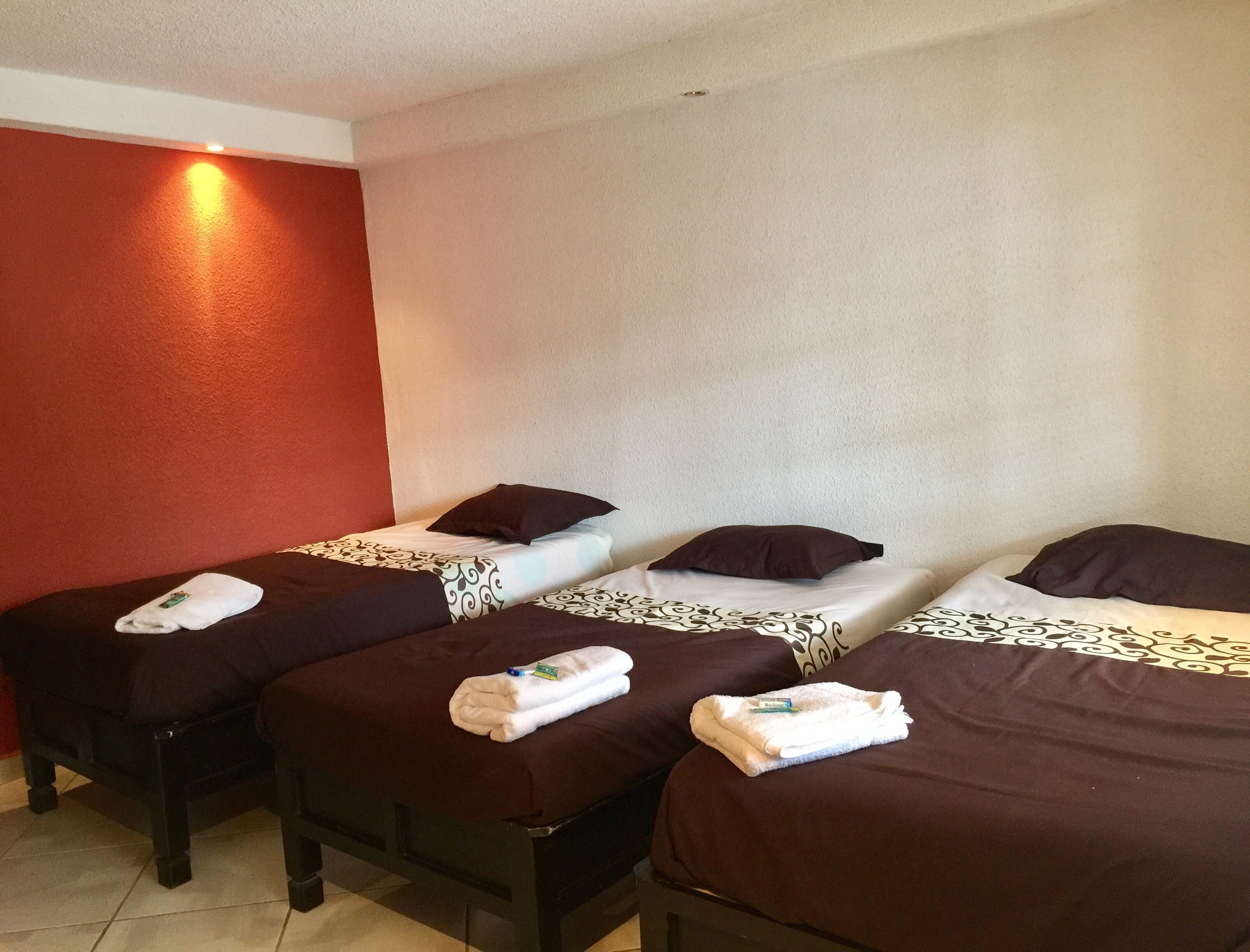 Quarto com quatro camas, cada uma com travesseiro e toalha dobrada.
