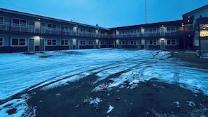 Um motel com vários andares e varandas, com um amplo estacionamento coberto de neve.