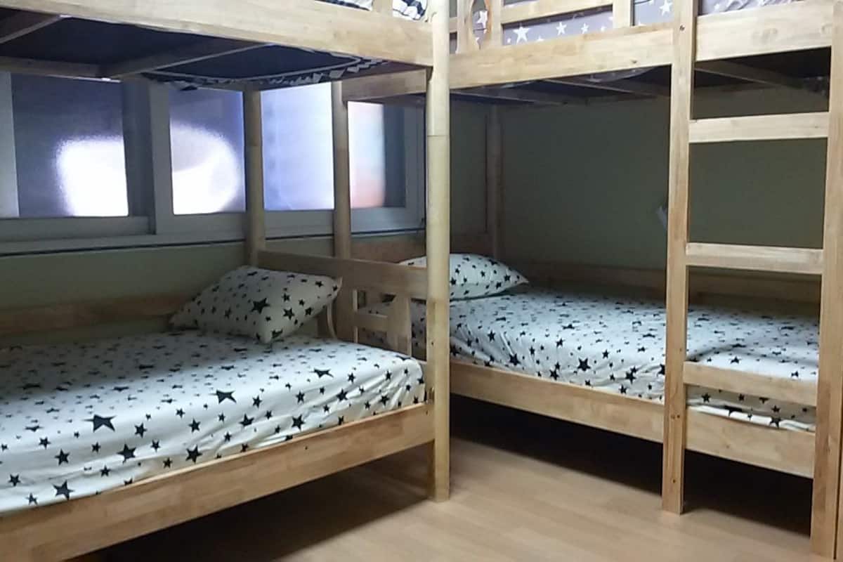 Quarto com beliches, roupa de cama estampada com estrelas e janela com vidro fosco.