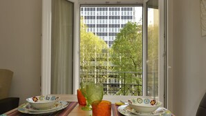 Uma mesa de jantar com vista para um prédio e árvores através de uma janela.