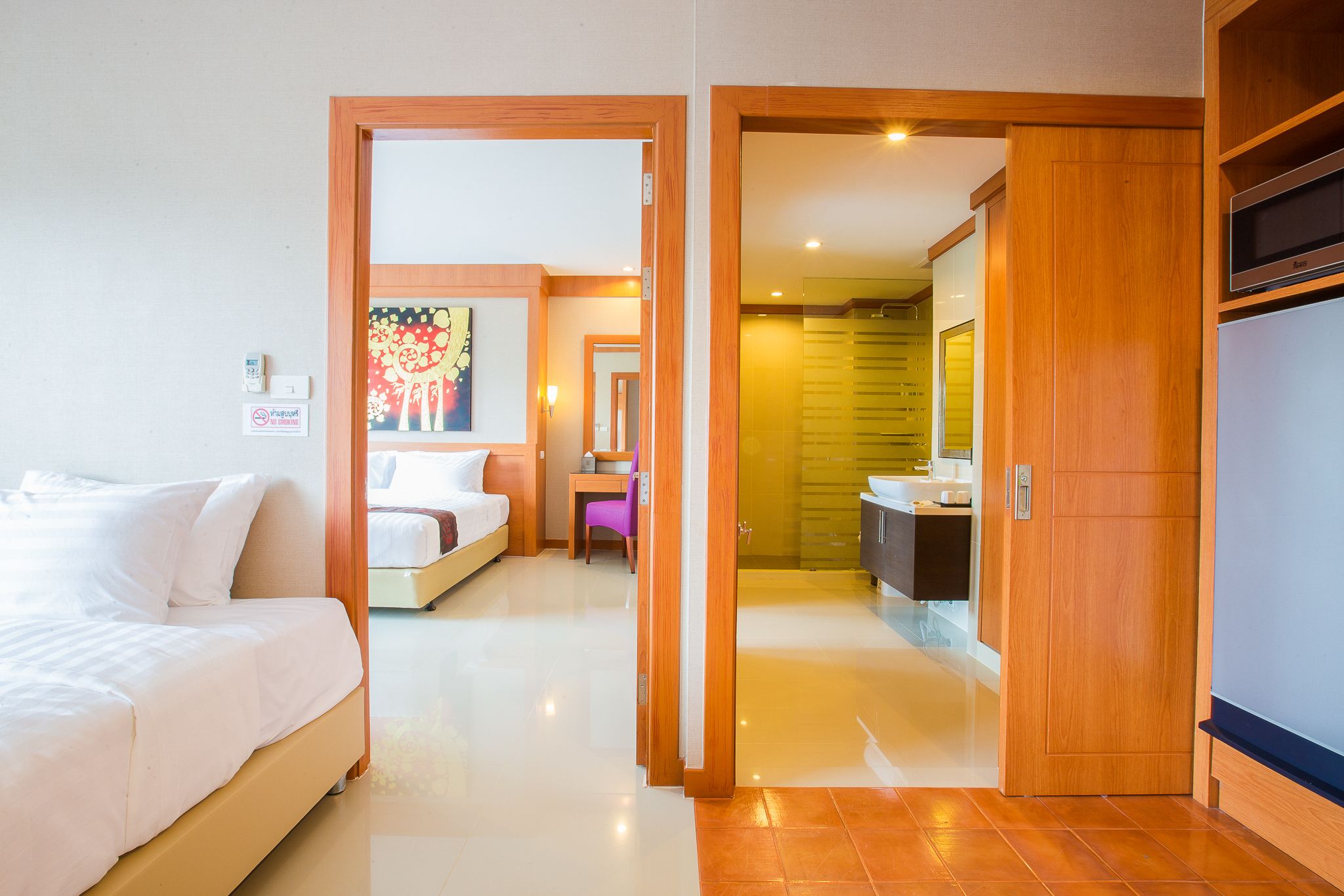 Quarto de hotel com cama, secretária, cadeira, banheiro e guarda-roupa.