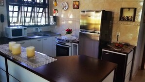 Cozinha equipada com micro-ondas, fogão, frigorífico, pia e janela com persianas.