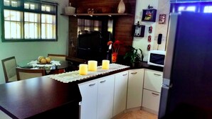 Uma cozinha com mesa de jantar, velas, geladeira e micro-ondas.