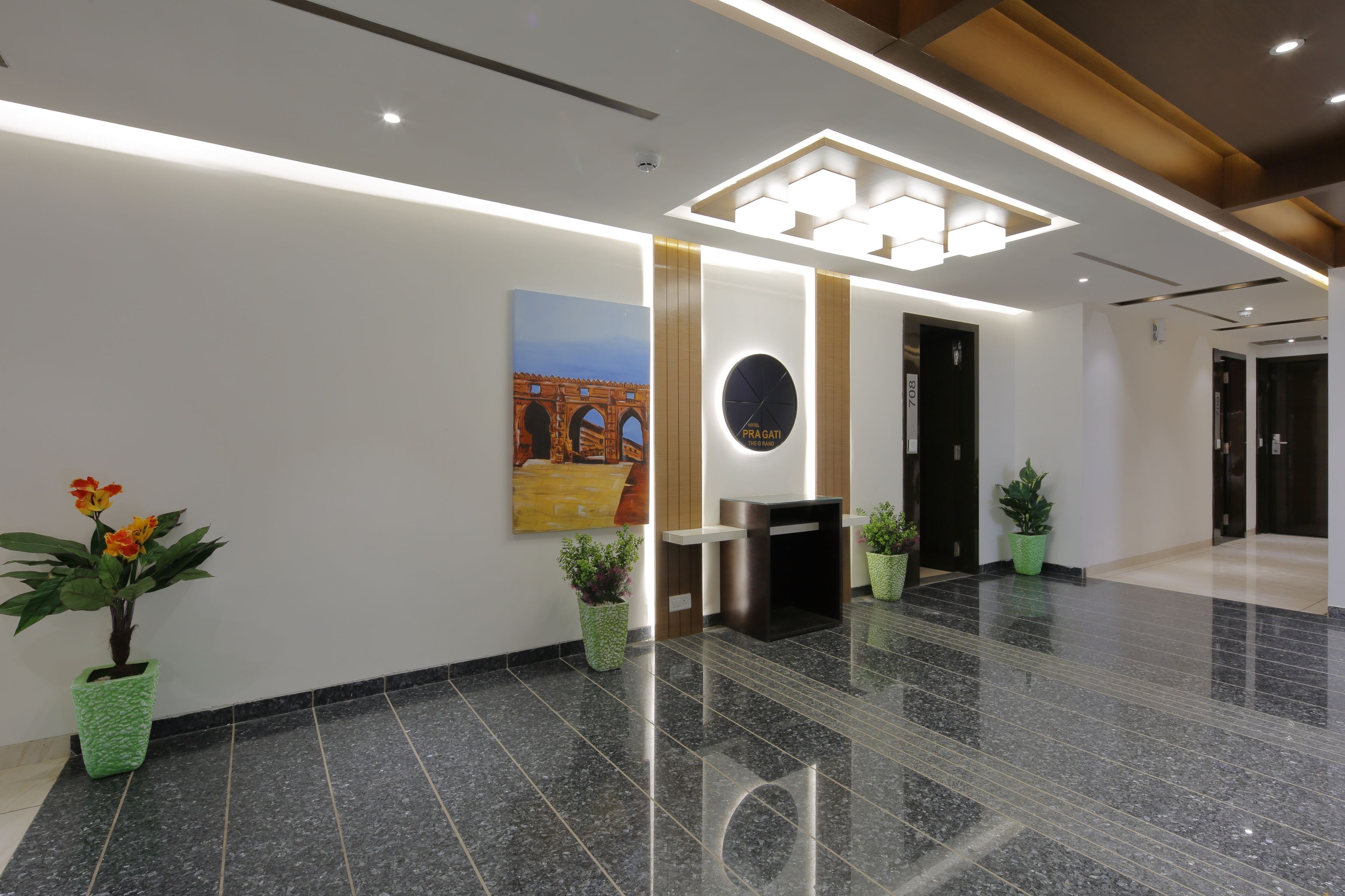 Um saguão de hotel moderno com piso de mármore polido, balcão de recepção e plantas em vasos.