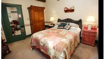 Quarto com uma cama grande, duas mesas de cabeceira com luminárias, um guarda-roupa de madeira e um espelho.